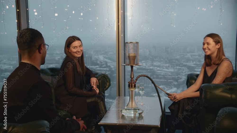 Vídeo do Stock: Man meets women in hookah bar. Media. Man sits down with young women to meet in ...