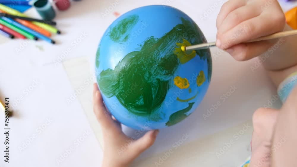 Child making planet for earth day from balloon. drawing blue ball with ...