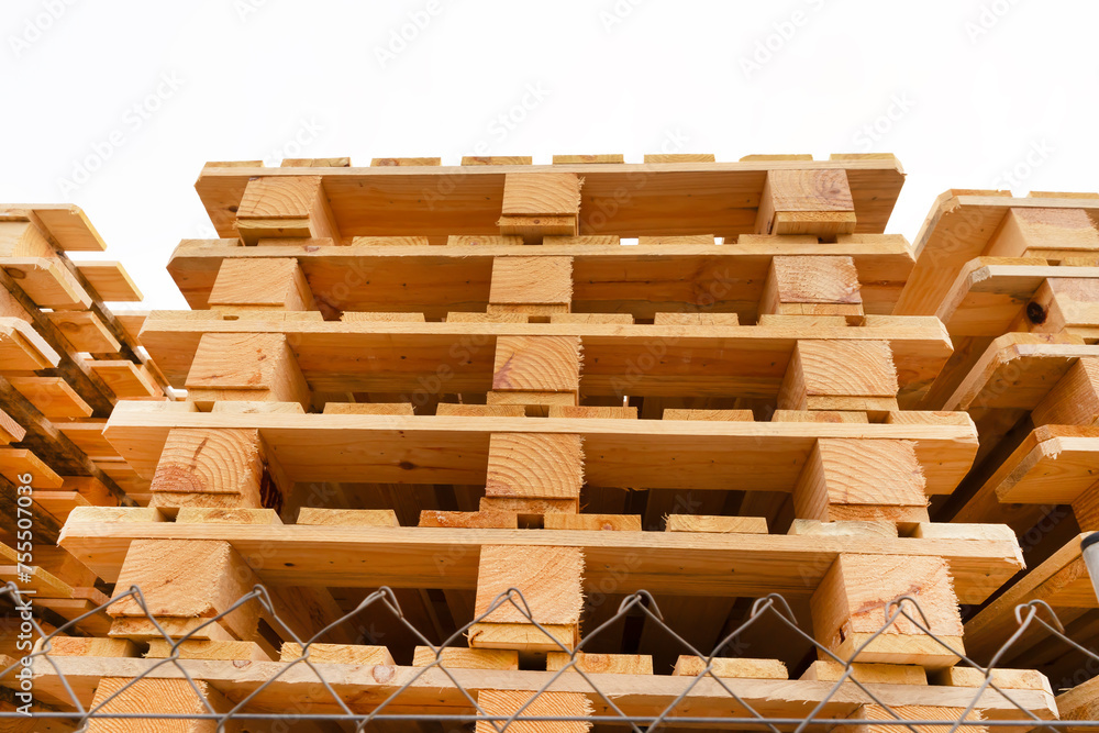 Pallets assembled from fresh sawn wood boards are stacked high on top ...
