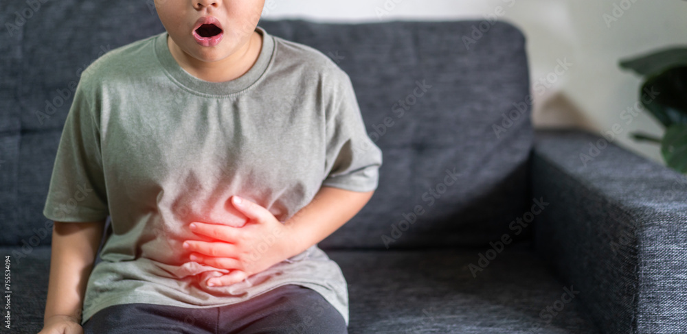 Portrait of sick unhappy little child asian boy touching belly stomach ...