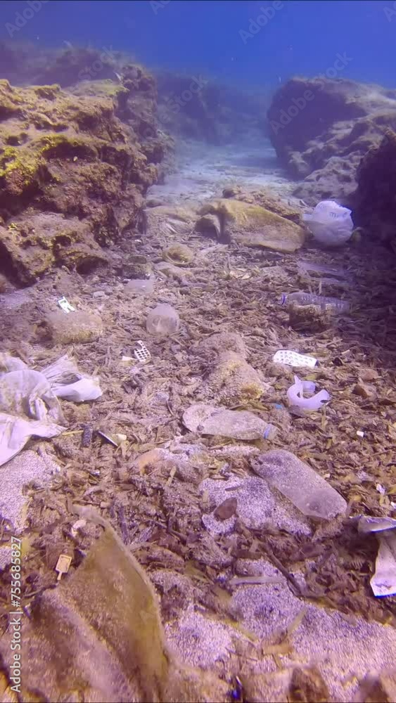 Vertical video, Lots of plastic refuse polluted sea bed in crevice ...