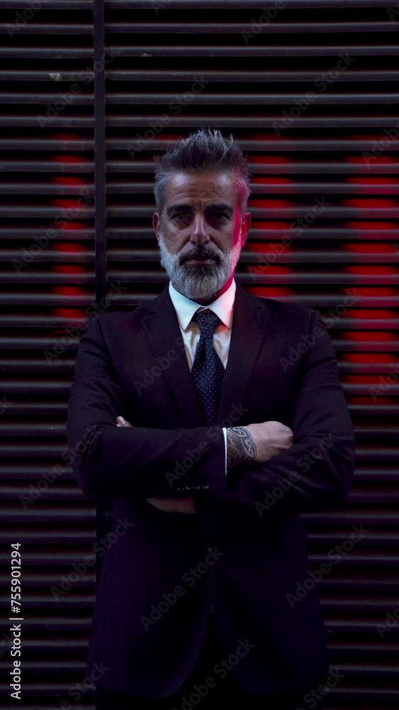 Businessman with commanding presence stands with arms crossed in front ...