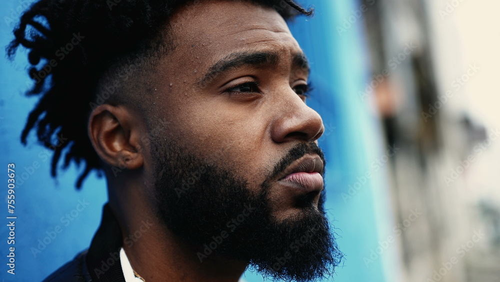 One pensive young black man standing in city street gazing with ...