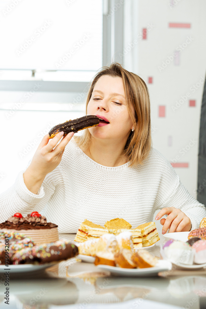 Woman eating pastry with cream, picking what to eat sitting beside ...