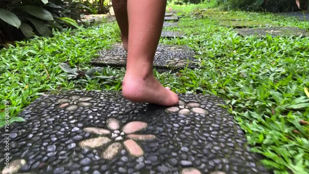 Joyful child runs barefoot on grass in tropical garden on Island. Close ...