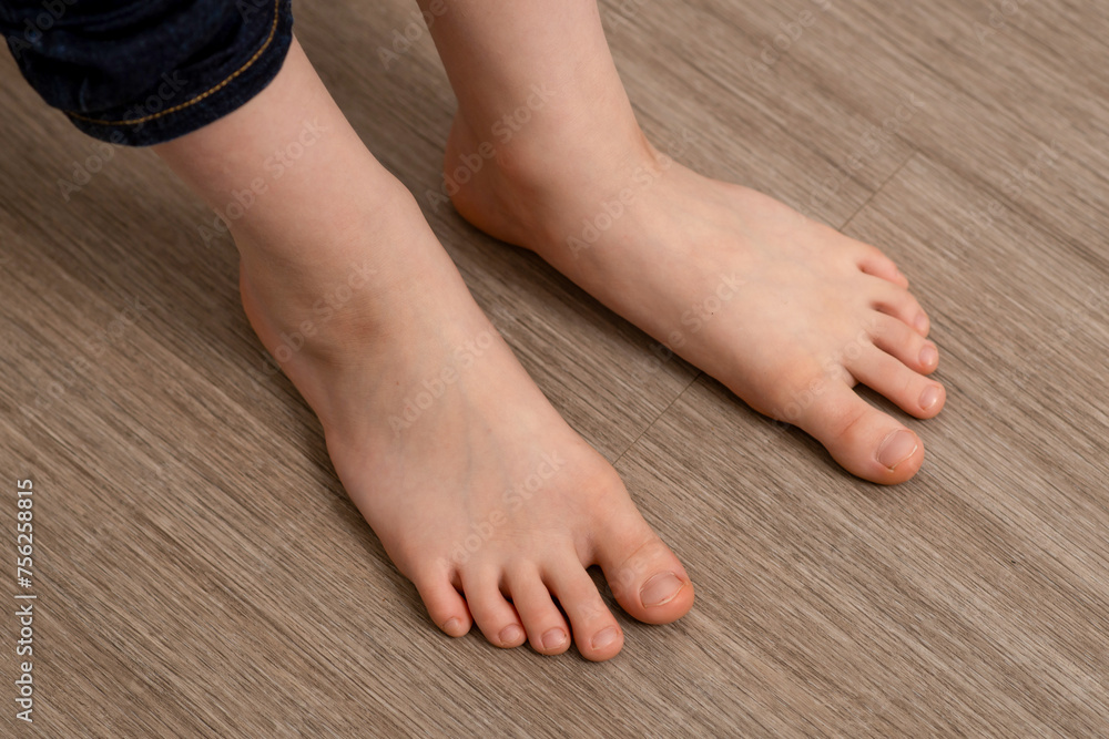 Innocent bare feet of a child rest on the ground, portraying the ...
