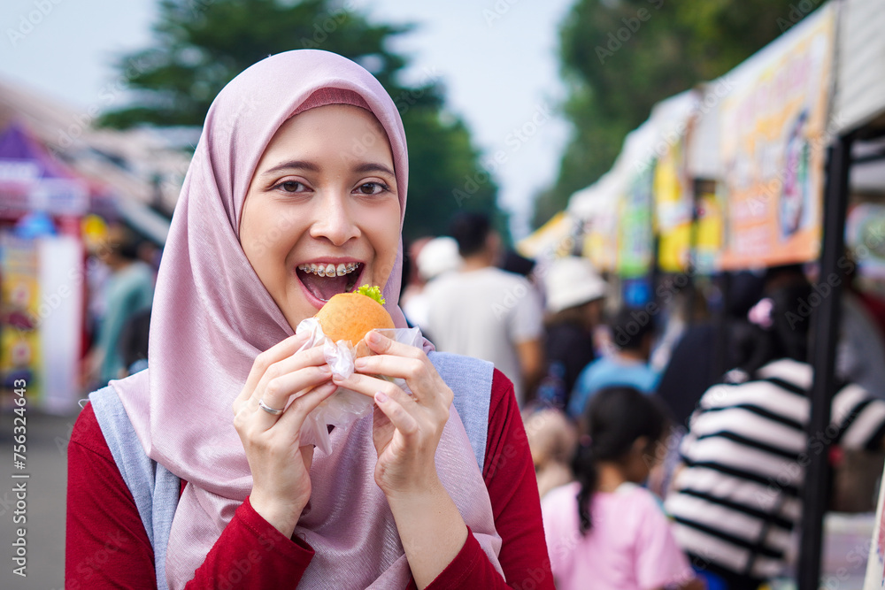 Muslim woman in hijab eating street food burger, street food concept ...