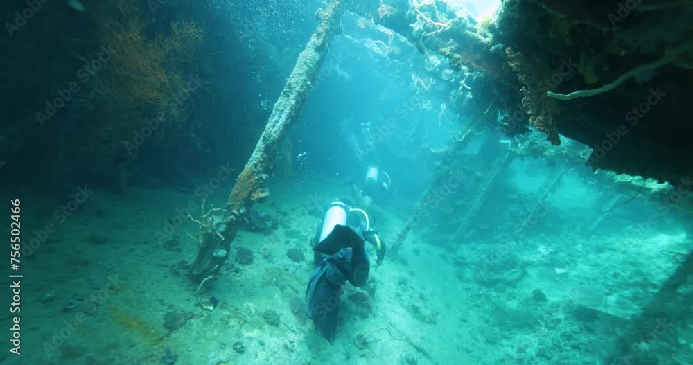 A group of divers diving towards a sunken ship in the Philippine Sea ...