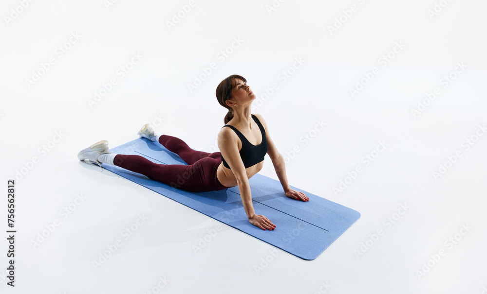 Young slim woman taking care after body condition, doing yoga exercises ...