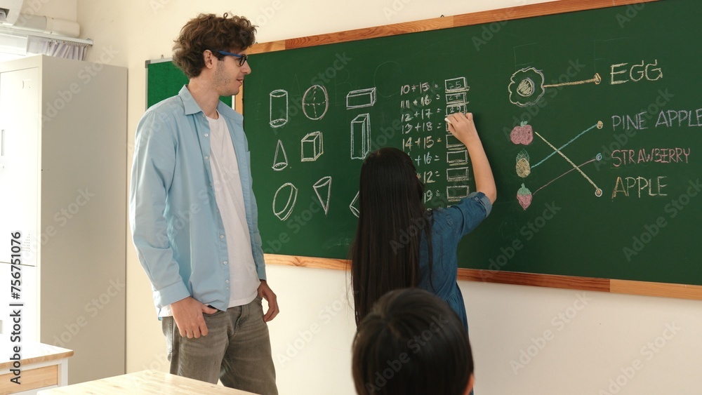 Young asian girl writing math formula at blackboard while standing at ...