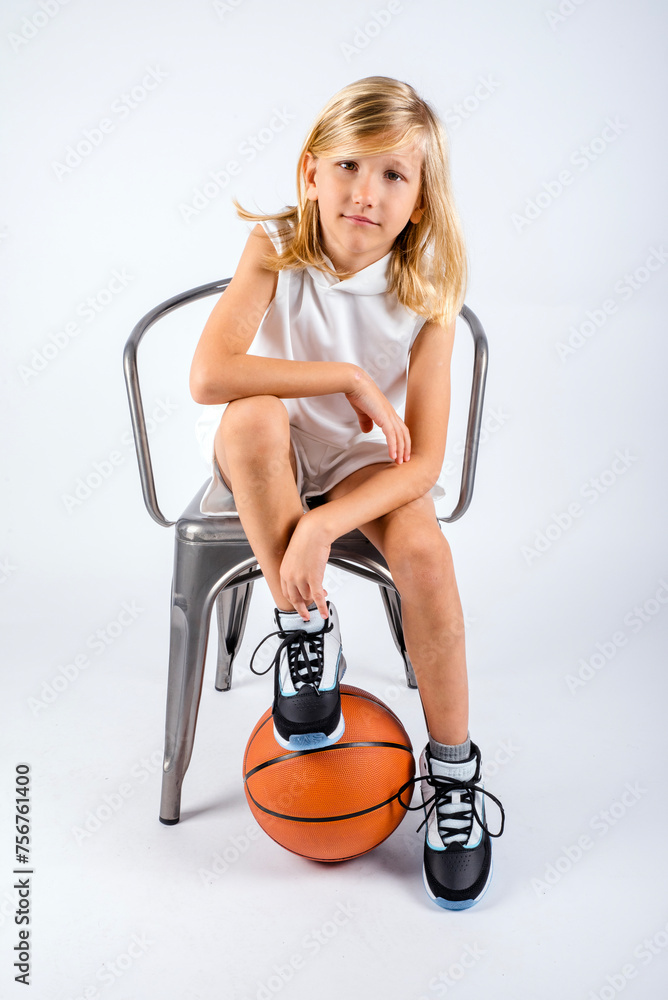 Cute little blond basketball player sitting in chair with his foot ...