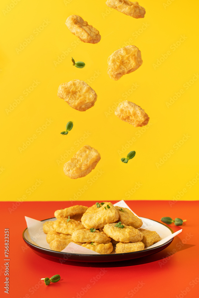 Delicious golden chicken nuggets levitate over a plate on a red and ...