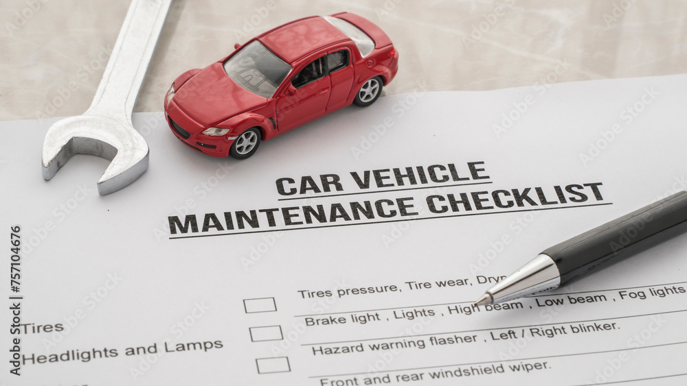 A car vehicle maintenance checklist on the table . A miniature car ...