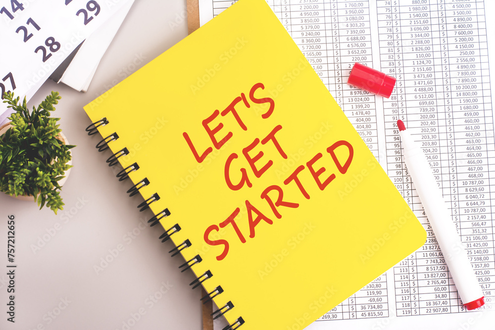 The yellow notebook with 'LET's GET STARTED' text on a grey background ...