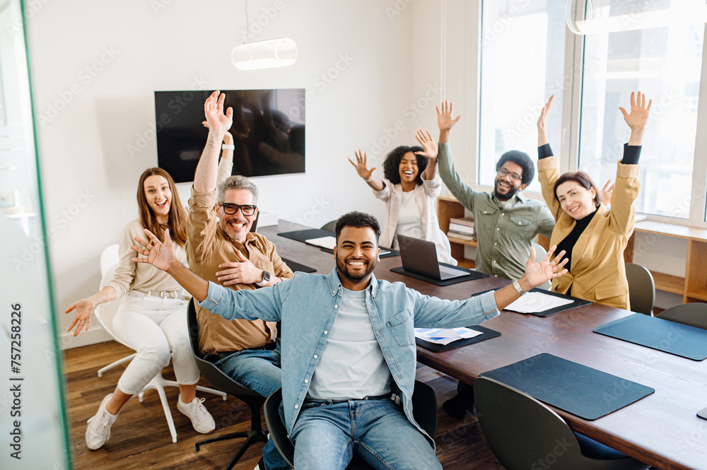 A vibrant office team celebrates with raised hands and beaming smiles ...