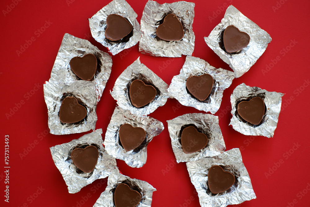 chocolate candies in the shape of a heart in a silver package on a red ...