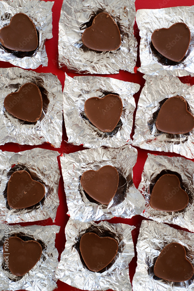 chocolate candies in the shape of a heart in a silver package on a red ...