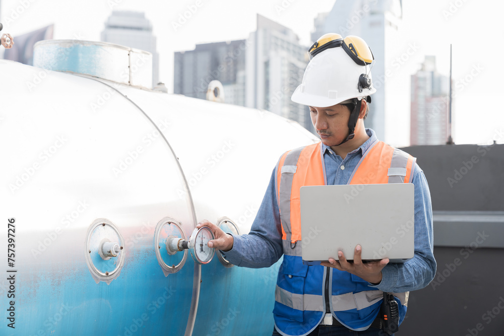 Asian male engineer working using laptop computer checks water tank at ...