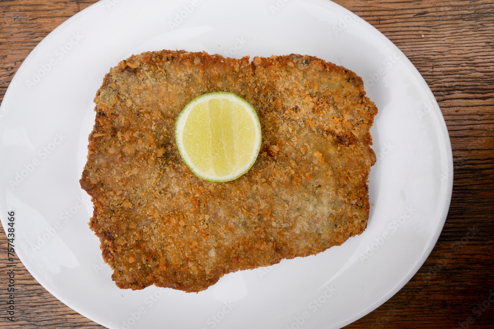 Argentine dish. Top view of milanesa, breaded fried steak, with a slice ...