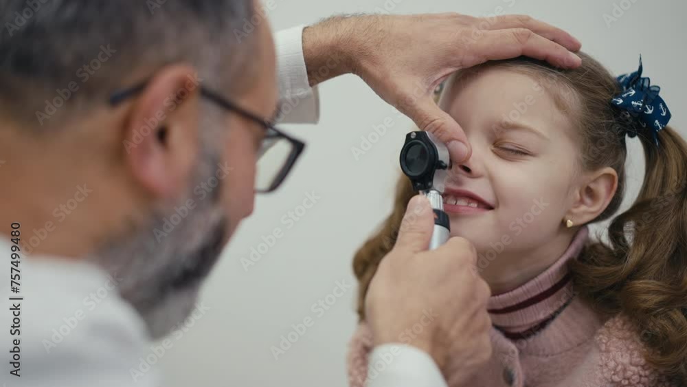 Close-up. A male pediatrician performs a visual examination of the ...