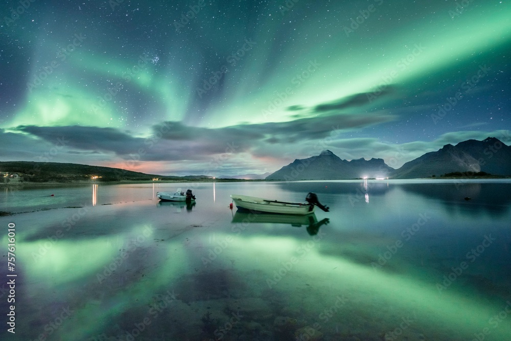 Small (Aurora borealis) motorboats anchoring in a bay, night view ...