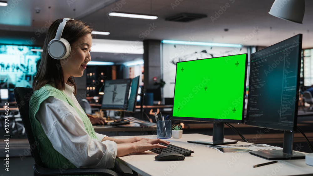 Female Asian Game Programmer Coding On Desktop Computer With Green