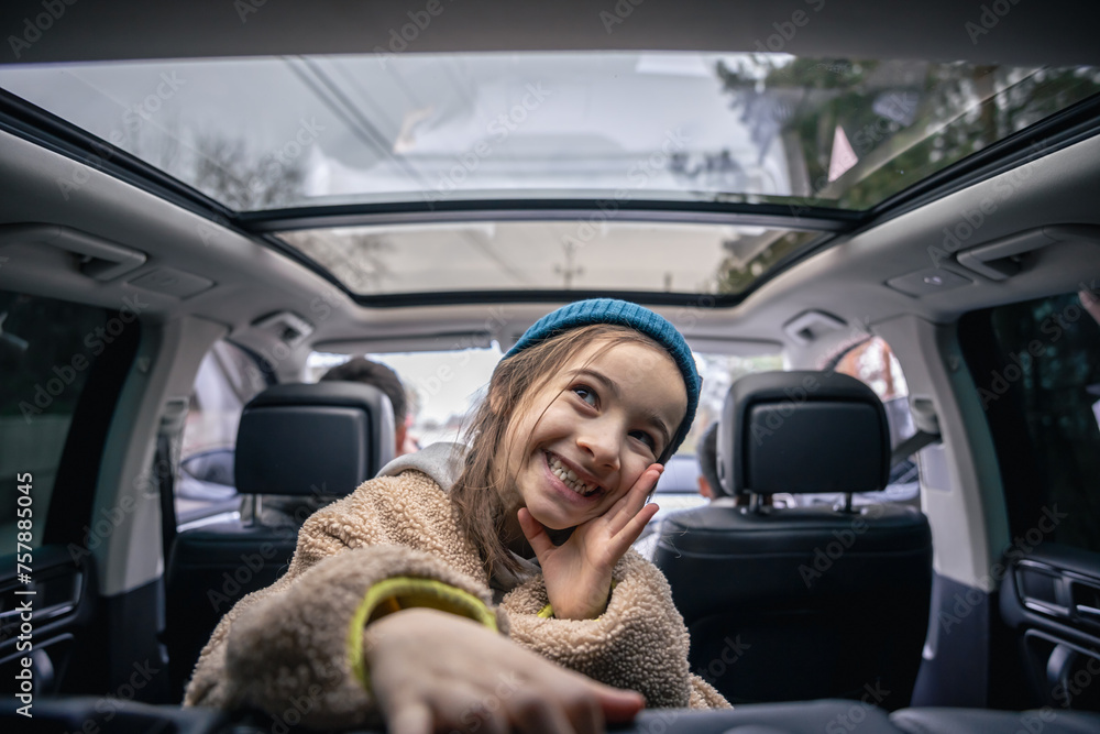 Funny little girl posing in the back seat of a car, playing in the car ...