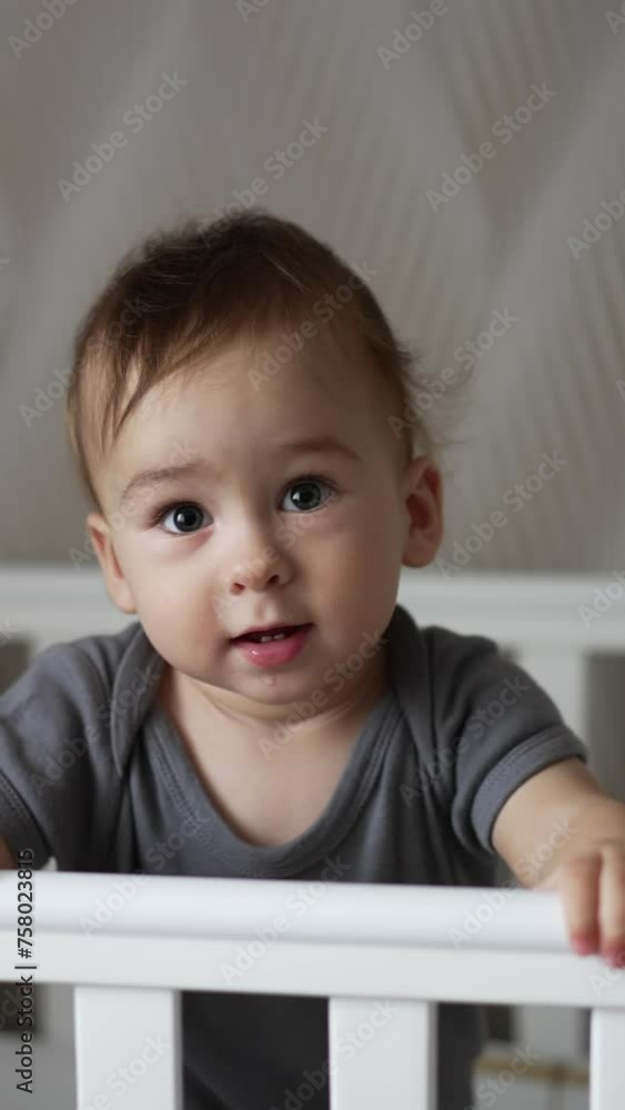 Lovely kid standing up in his cot holding by the handrails. Beautiful ...