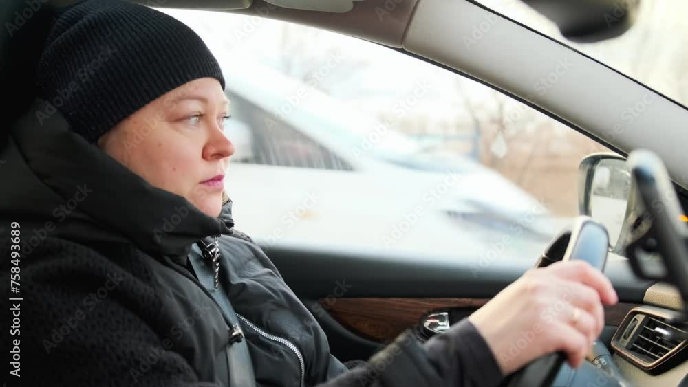 Close-up adult female driver in hat sitting behind wheel of car ...