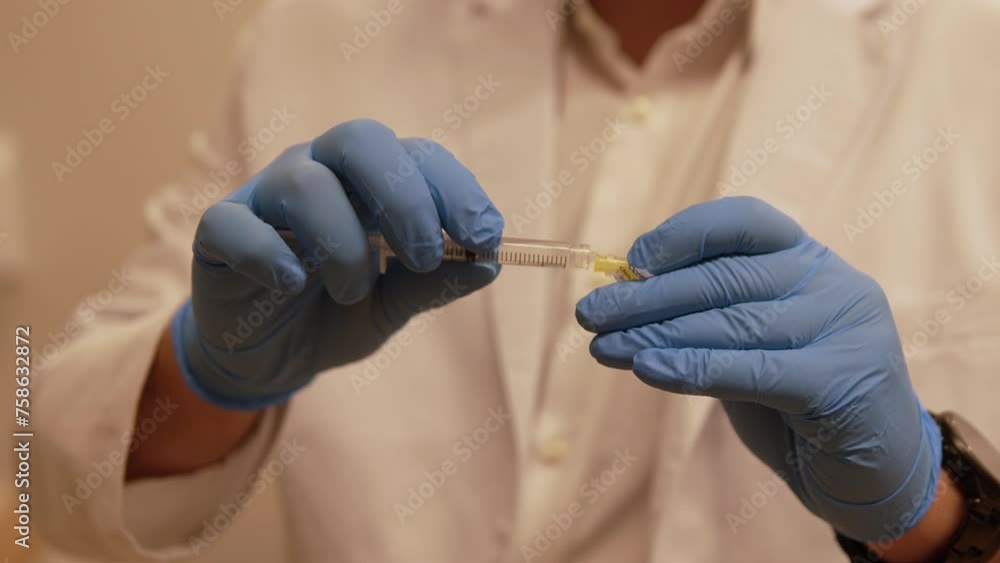 A medical professional prepares a syringe for use, demonstrating care ...