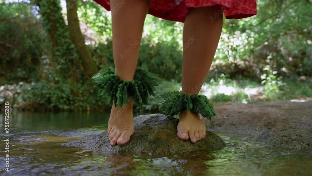 Detail shot of a woman's bare feet on a rock in the river dancing the ...
