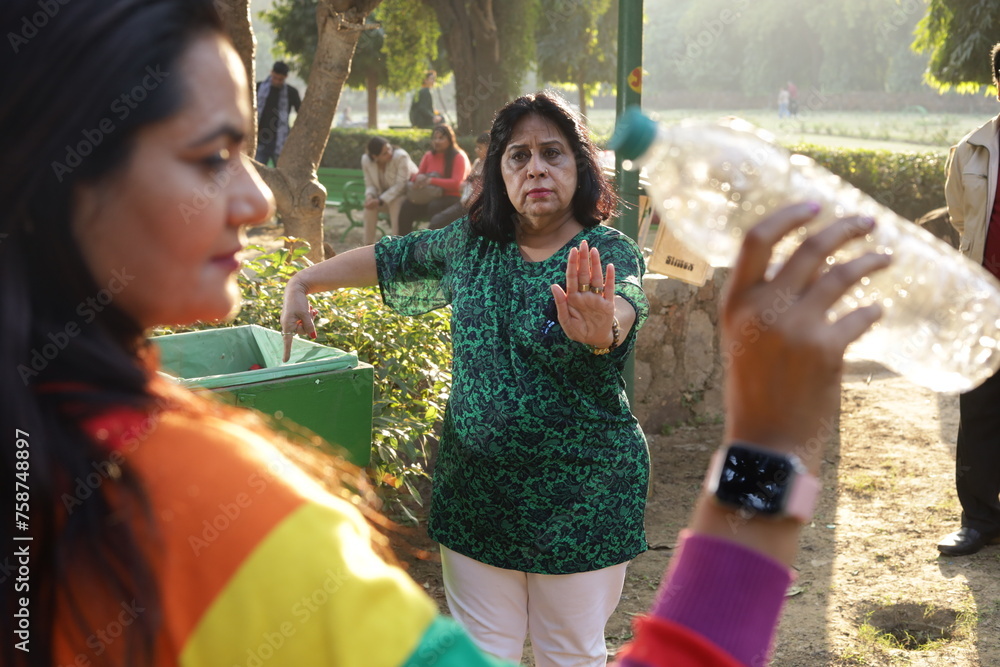 Woman telling young girl, not to throw garbage or plastic trash in park ...