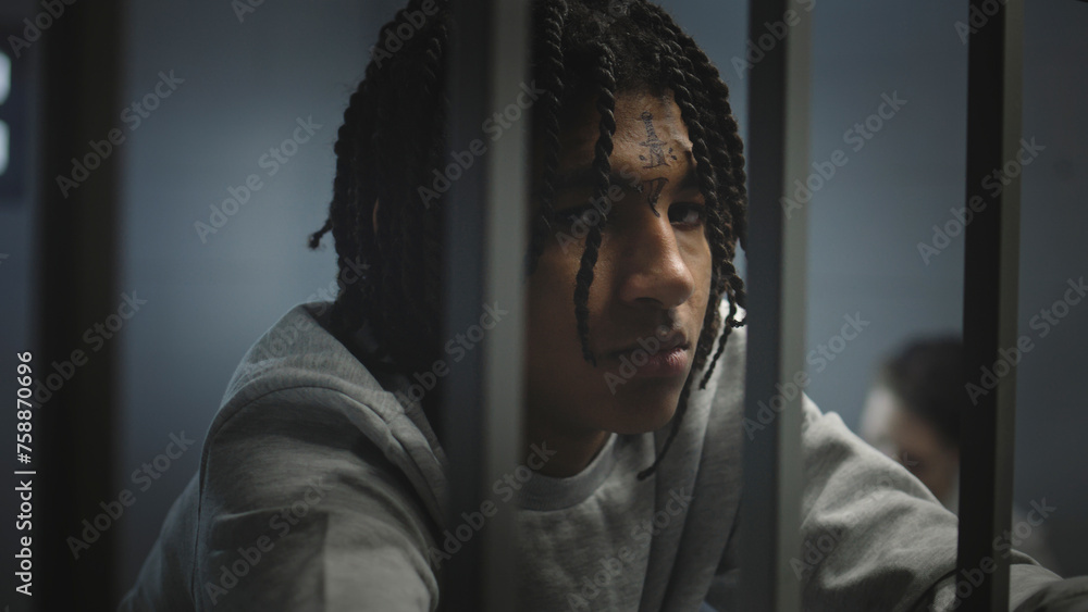 Angry African American teenage prisoner with face tattoos stands in ...