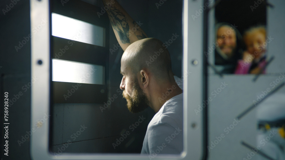 Reflection of male prisoner in mirror looking out the window in prison ...