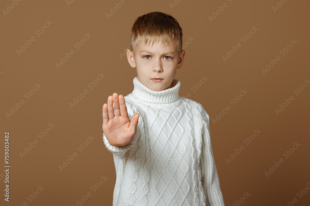 Portrait of serious, angry boy extends hand, shows stop gesture ...