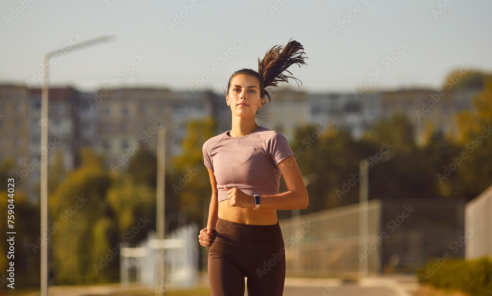 Confident calm woman in good physical shape running on city streets on ...