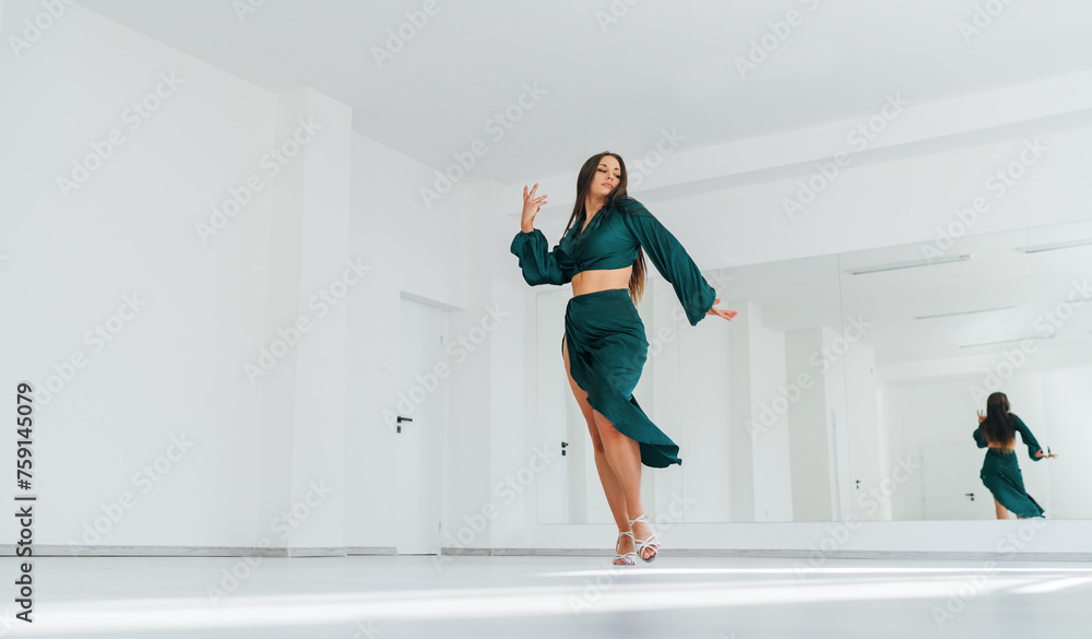 Graceful woman dressed in dark green Latin dancing dress doing elegant ...