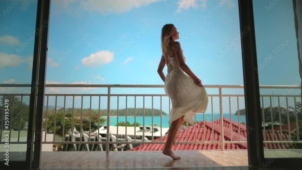 A woman in a white dress gracefully walks on a balcony overlooking a ...