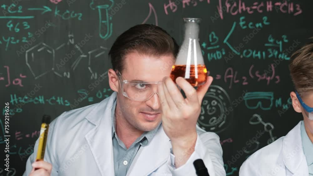Smart teacher holding solution in beaker while student doing experiment ...