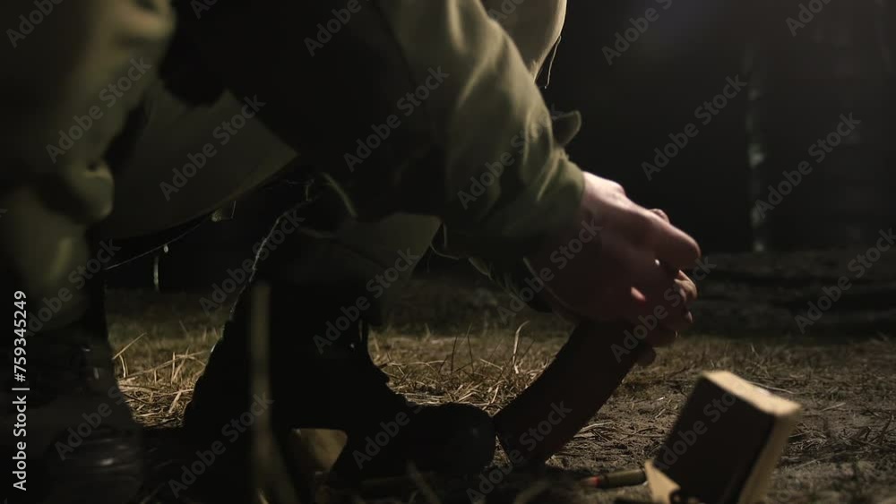 Soldier loads cartridges into a machine gun magazine, in the dark room ...