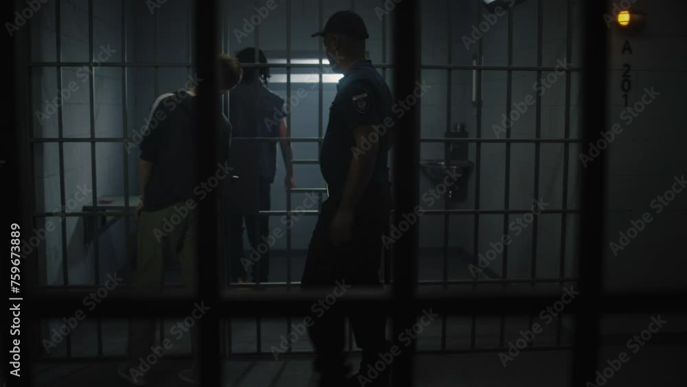 Warden brings young prisoner in jail cell and takes off his handcuffs ...