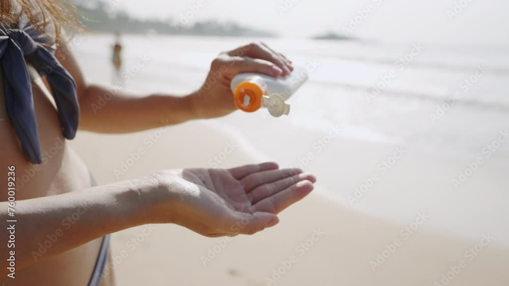 Female hands squeezing sun cream from bottle and applying on hand at ...