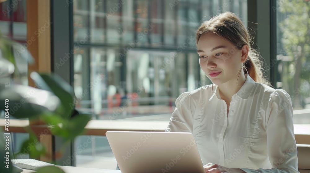 Smiling female employee typing browsing web on laptop in modern office ...