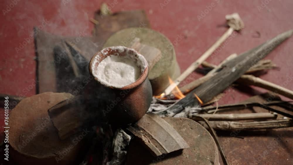 Sri Lankan woman prepares milk in clay pot, simmers on open flame. Milk ...