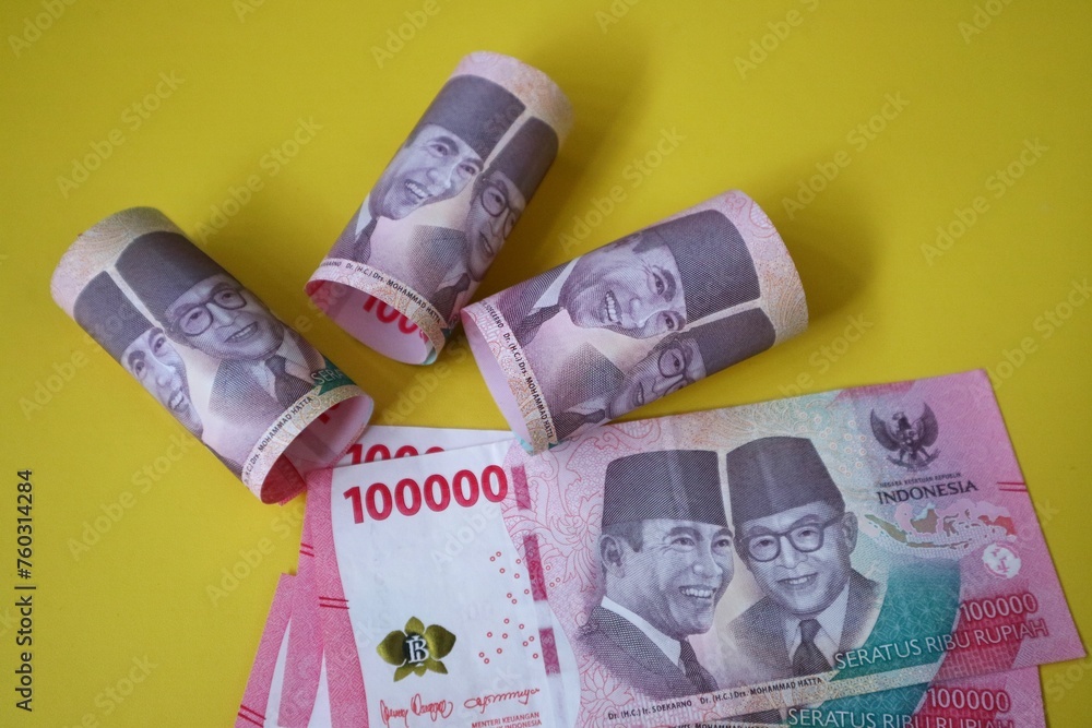 Rolled Indonesian Rupiah or IDR banknotes on the yellow background ...