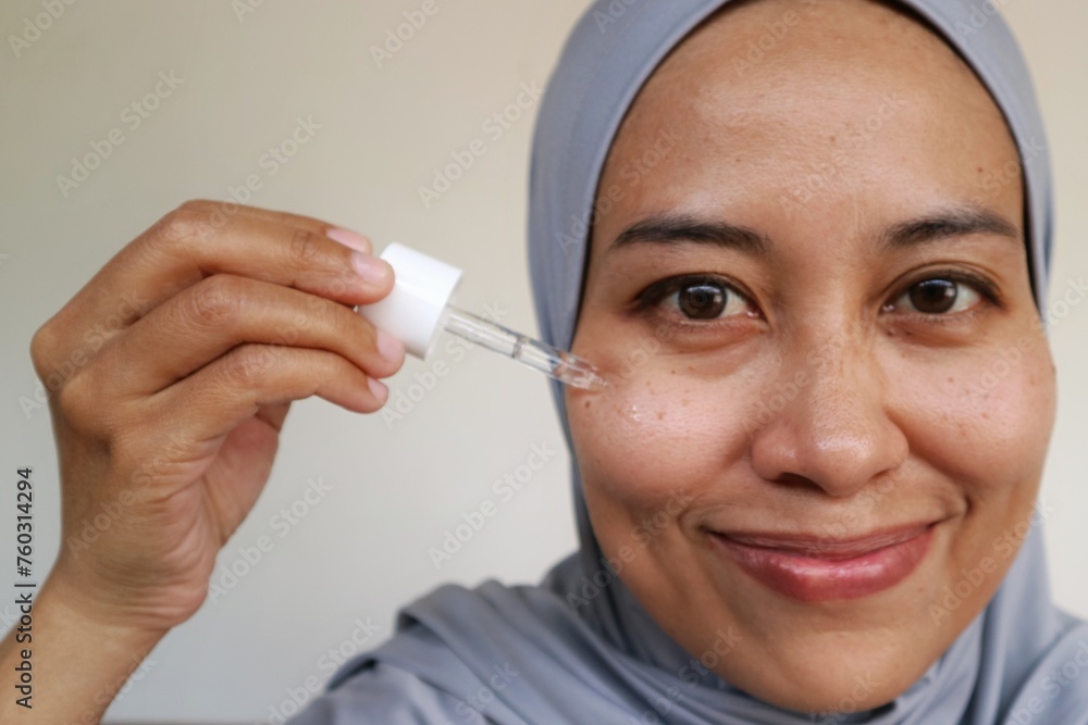 Half face of Happy muslim woman in hijab showing pipette with hydrating ...