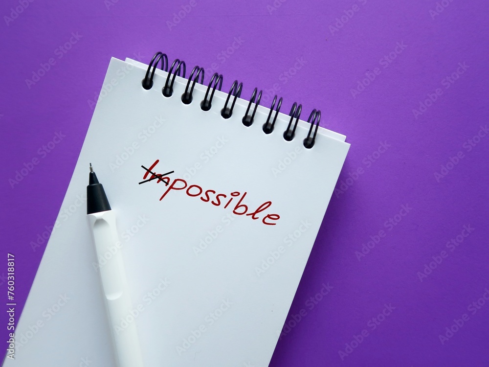 Notebook on purple background with text written IMPOSSIBLE crossed of ...