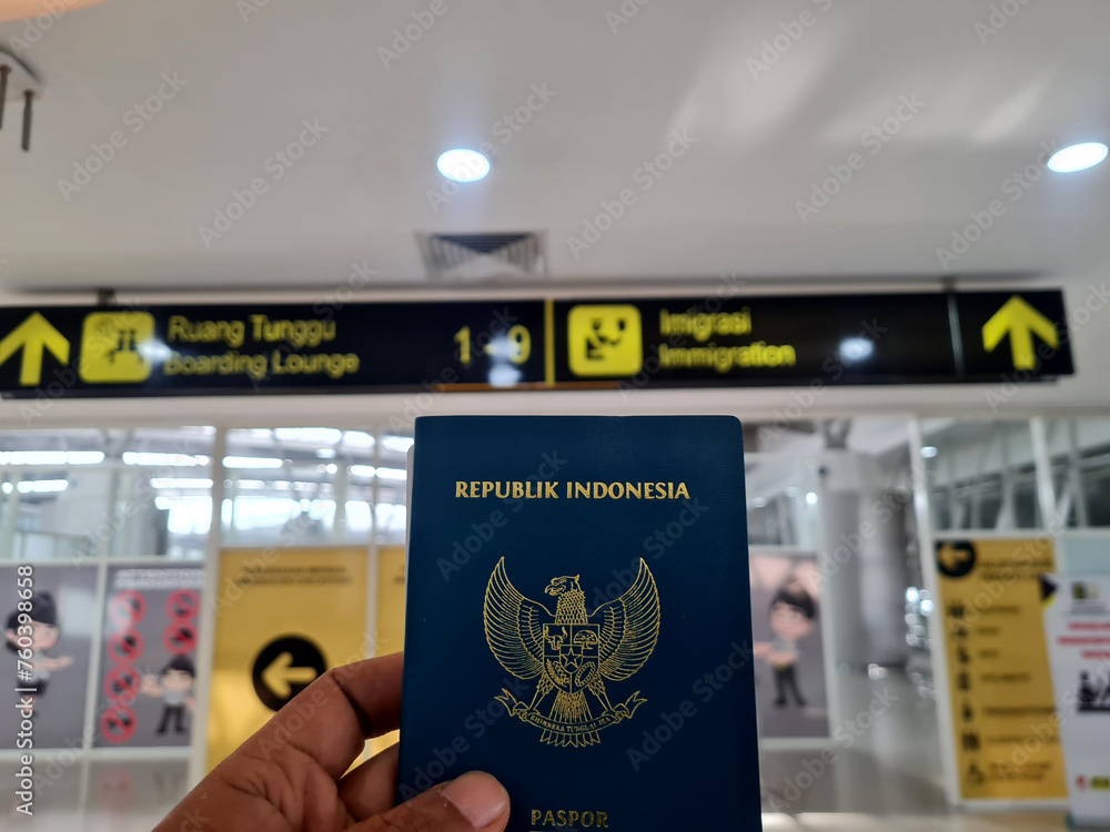 hand showing Indonesian passport with the background of the immigration ...