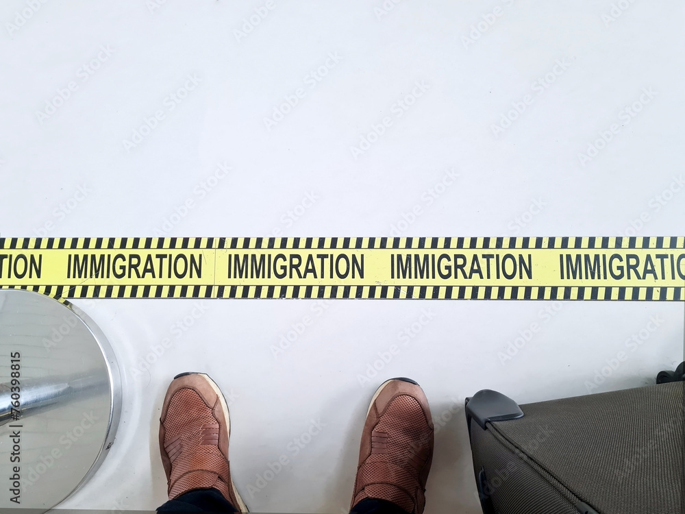 Travelers' footsteps stop at the yellow immigration border line ...