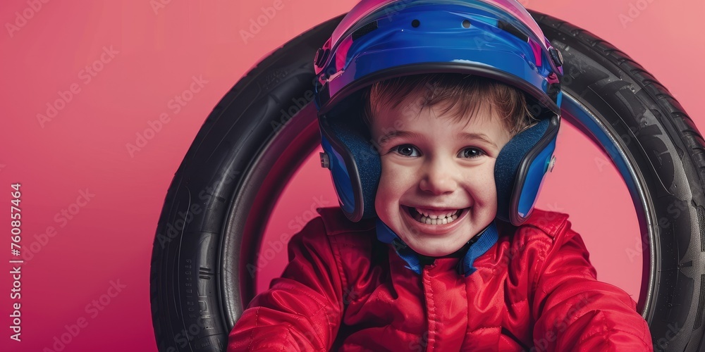Boy in helmet smiling through tire - Cheerful young boy in a red suit ...